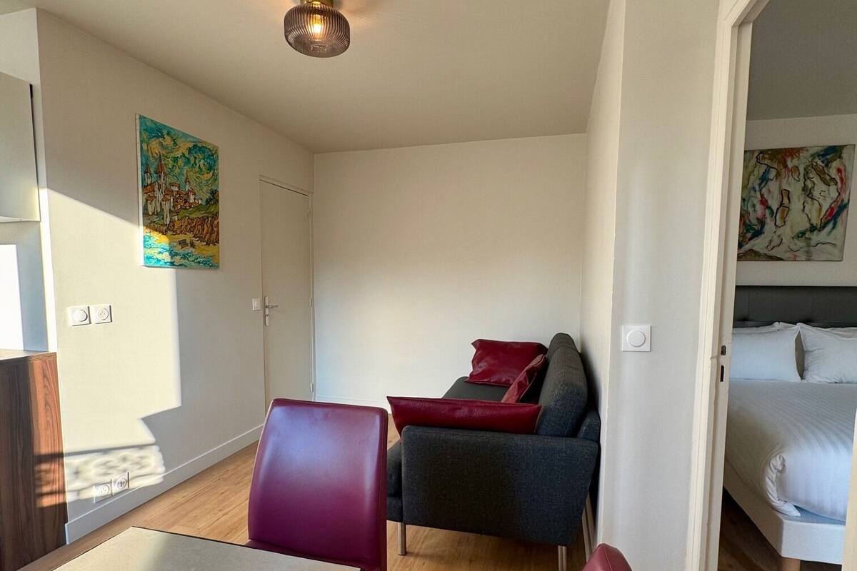 Quarto moderno com mesa de jantar, cadeiras, sofá e cama.