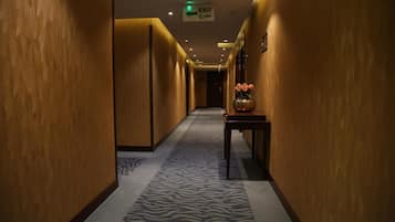 Corredor de hotel com paredes de madeira, carpete estampado com padrão de zebra e sinalização de saída.