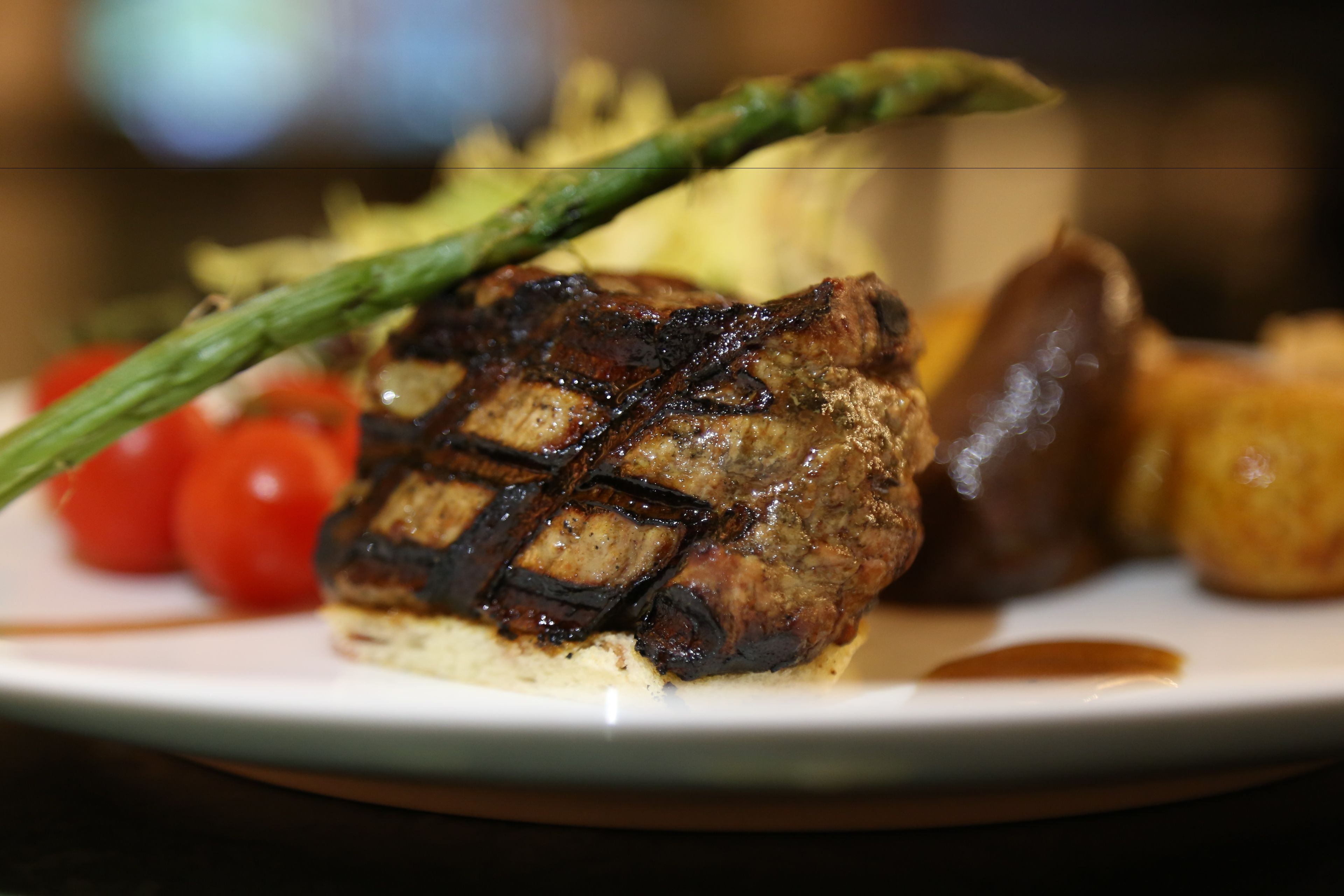 Um prato com bife grelhado, aspargos e tomates cereja.