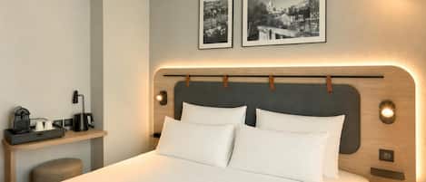 Quarto de hotel moderno com uma cama grande, mesas de cabeceira e quadros na parede.