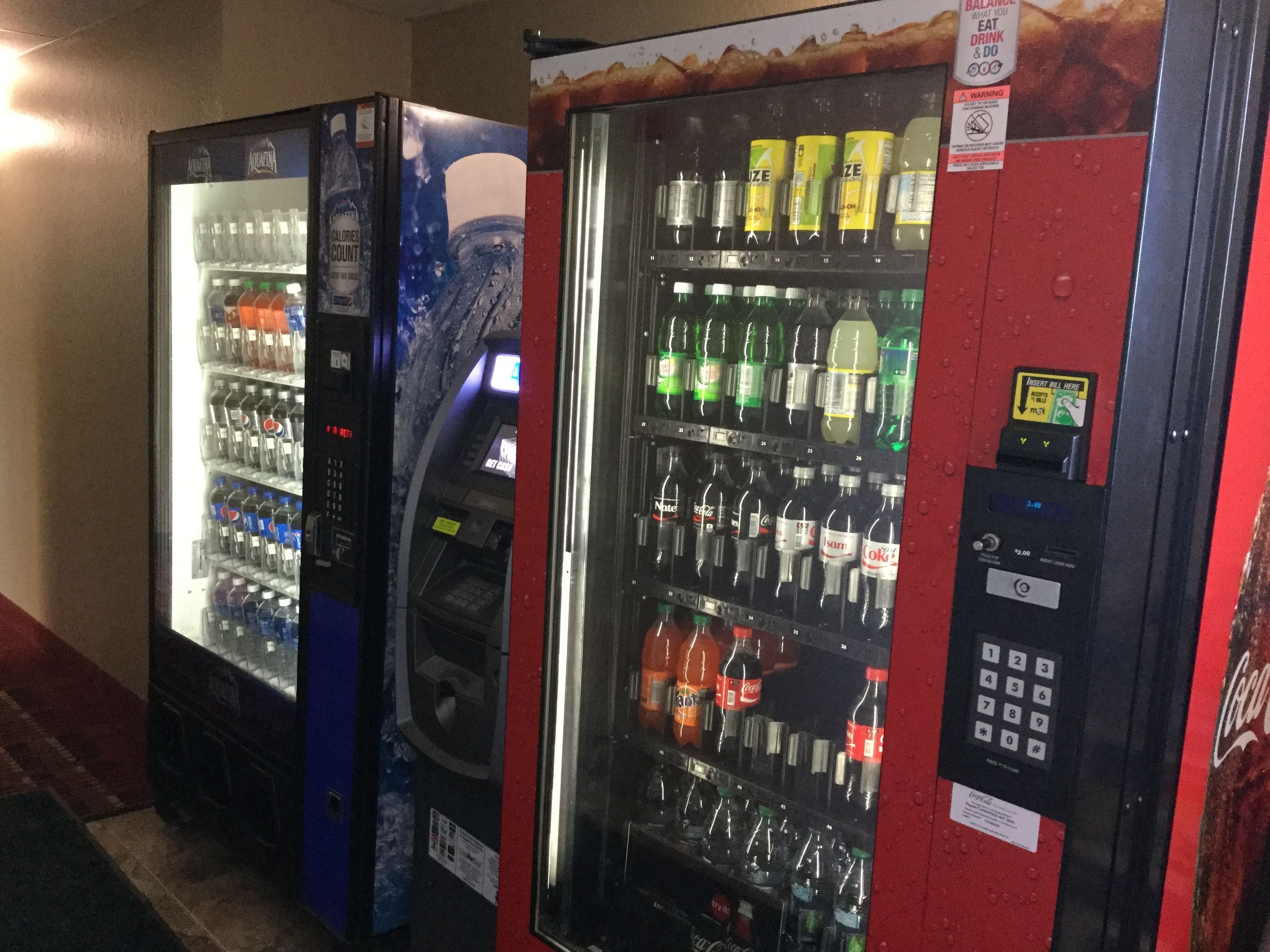 Uma fileira de máquinas automáticas com diversas bebidas e petiscos.