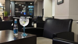Ambiente de restaurante com mesa, cadeiras e um copo de água ao lado de uma garrafa.