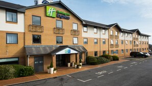 Um hotel Holiday Inn Express com fachada de tijolos, várias varandas e estacionamento.