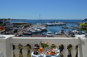 Varanda com mesa posta para o café da manhã, com vista para uma marina cheia de barcos e iates.
