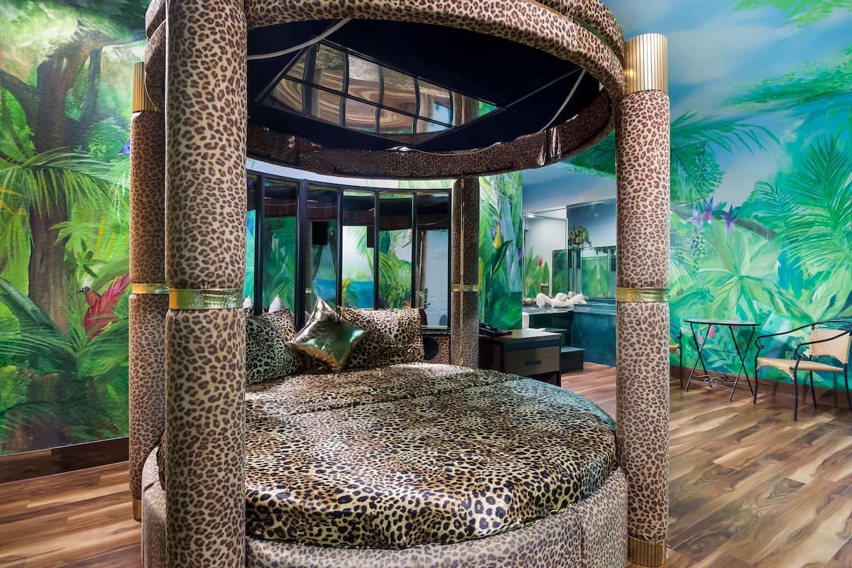 Quarto com cama redonda, decoração em estampa de leopardo e uma janela grande.