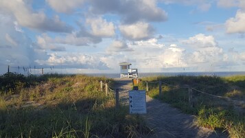Uma trilha na praia que leva a uma torre salva-vidas, com uma placa sobre a proteção das tartarugas marinhas.