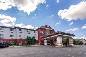 Um hotel Best Western Plus com fachada em vermelho e bege, entrada coberta e estacionamento.