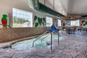 Área da banheira de hidromassagem com um mural, uma janela e um espaço de estar com mesas e cadeiras.