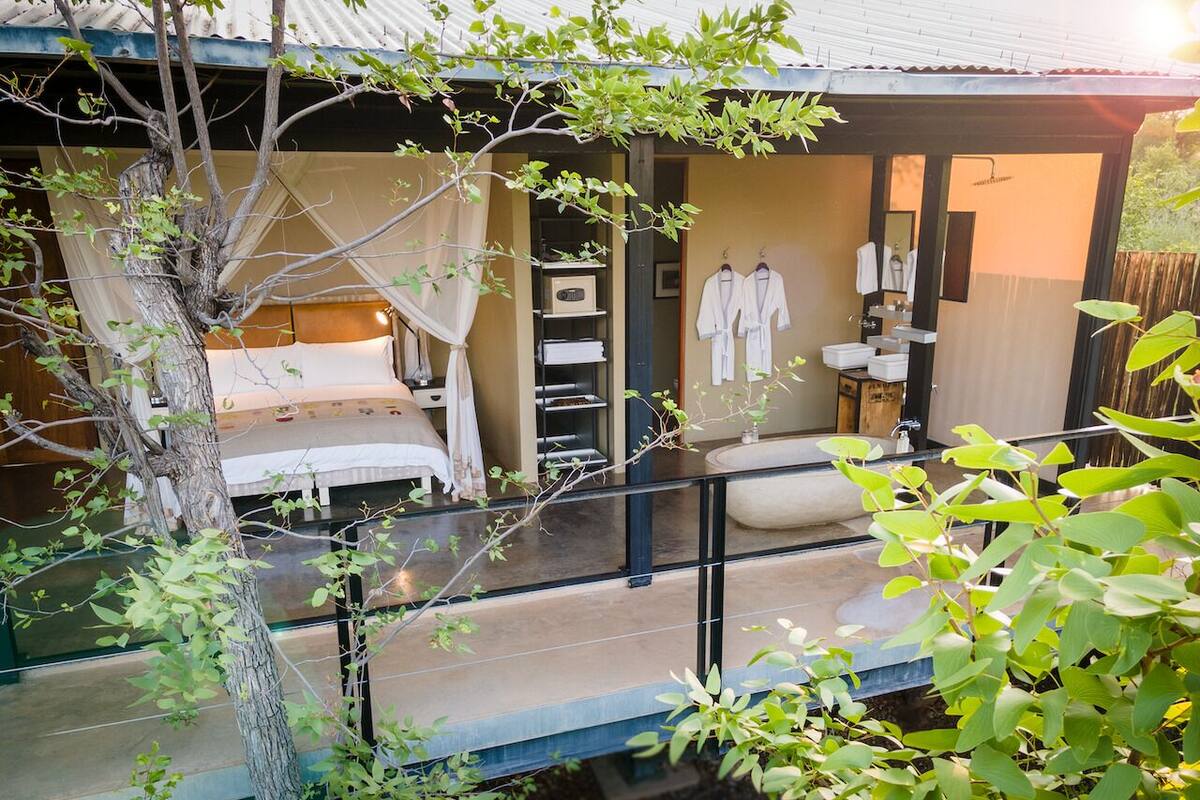 Quarto com cama, banheiro com pia e espelho, e varanda com guarda-corpo.