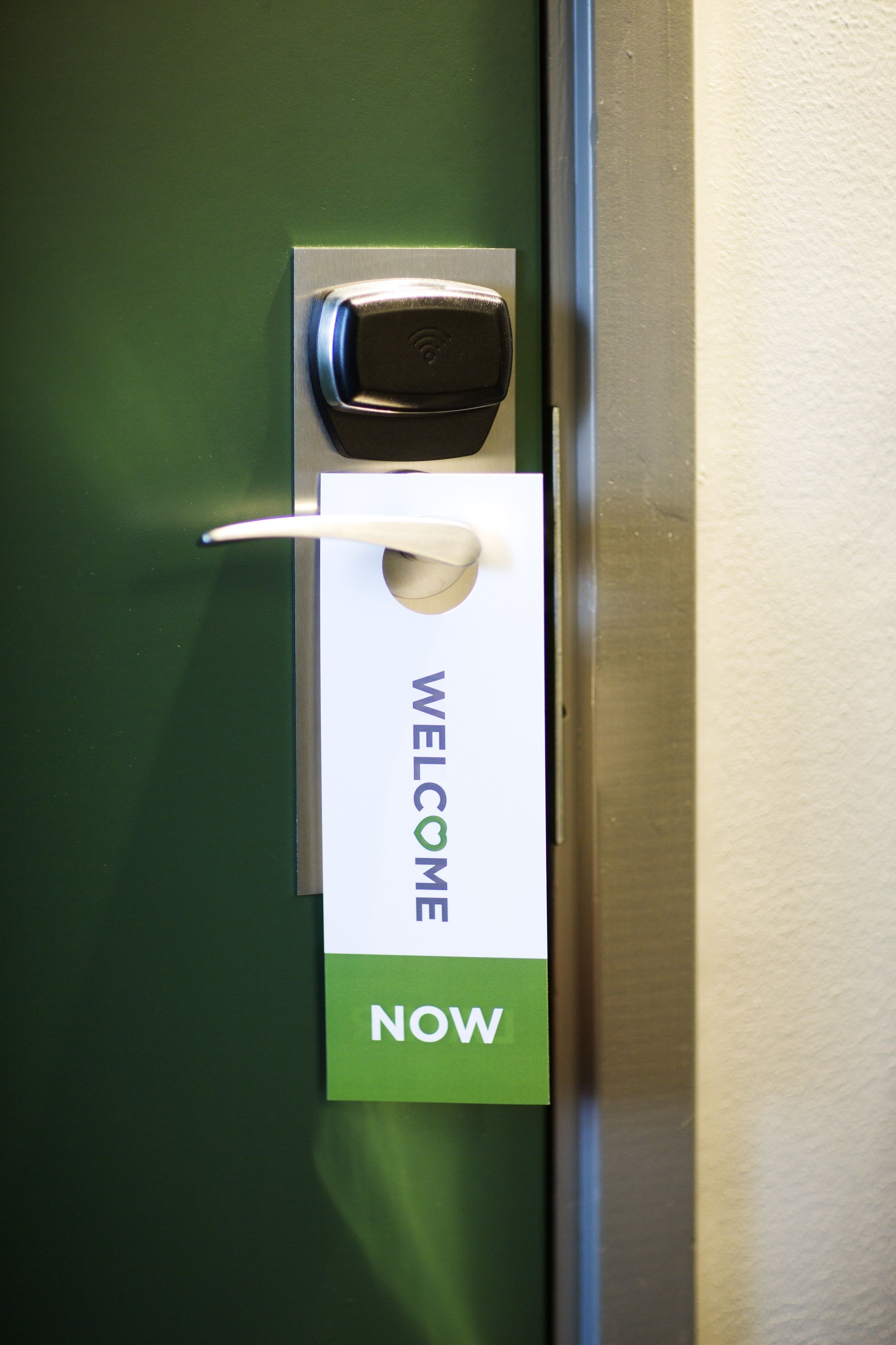 Uma porta com uma placa de 'WELCOME' e um botão 'NOW'.