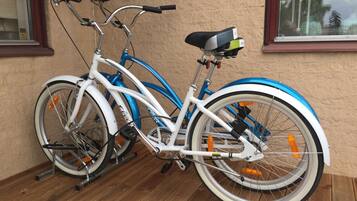 Uma bicicleta branca e azul encostada a uma parede, com uma janela ao fundo.