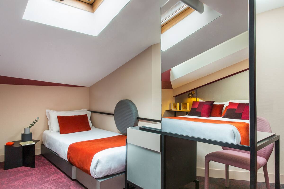Quarto com cama, escrivaninha, cadeira e espelho.