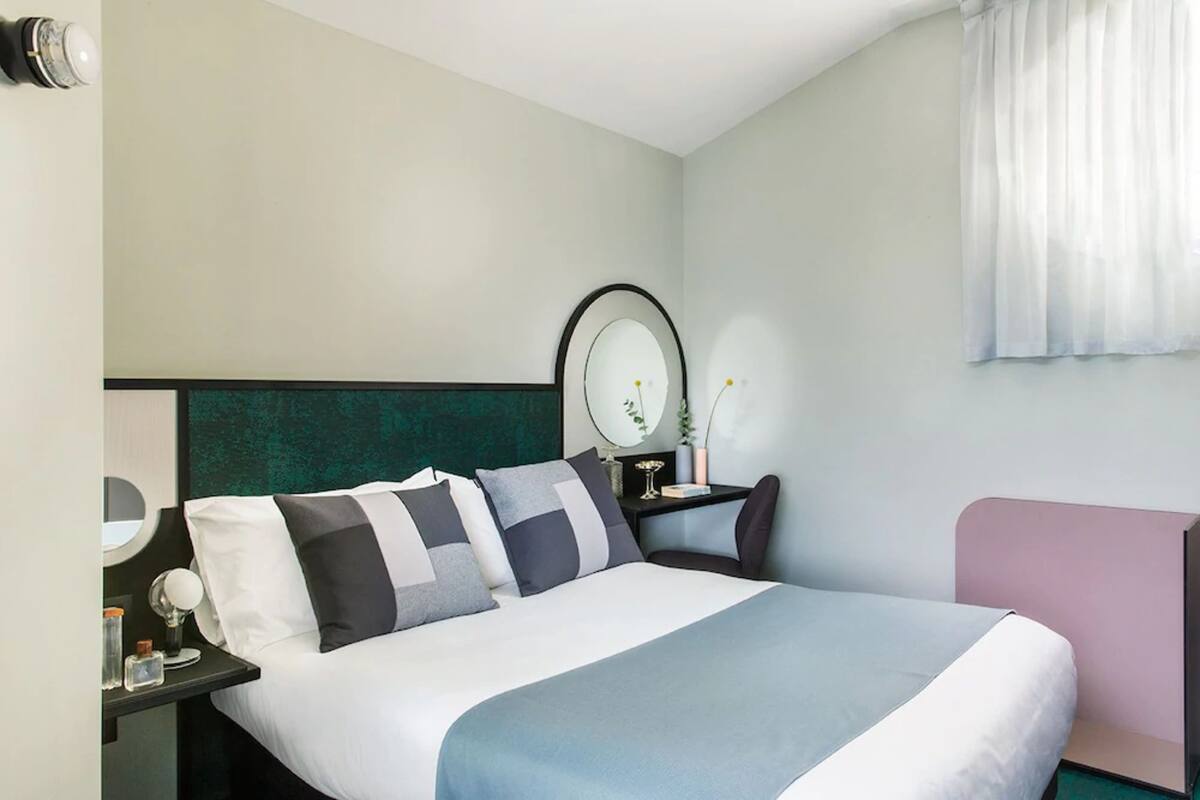 Quarto de hotel bem organizado, com cama, mesa de cabeceira e uma cadeira.