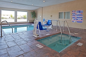 Piscina interior com sinalização clara, cadeira de salva-vidas e elevador de piscina.