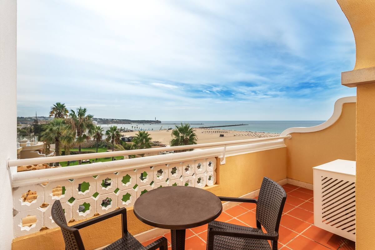Varanda com vista para a praia, uma mesa e duas cadeiras.