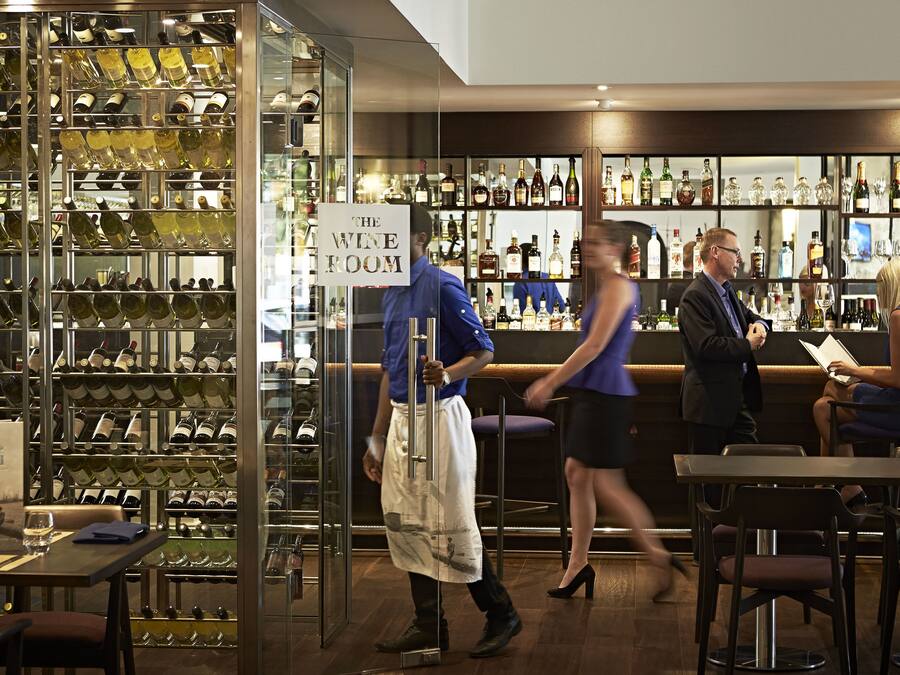Uma adega com prateleiras cheias de garrafas de vinho e um letreiro com a inscrição 'The Wine Room'.