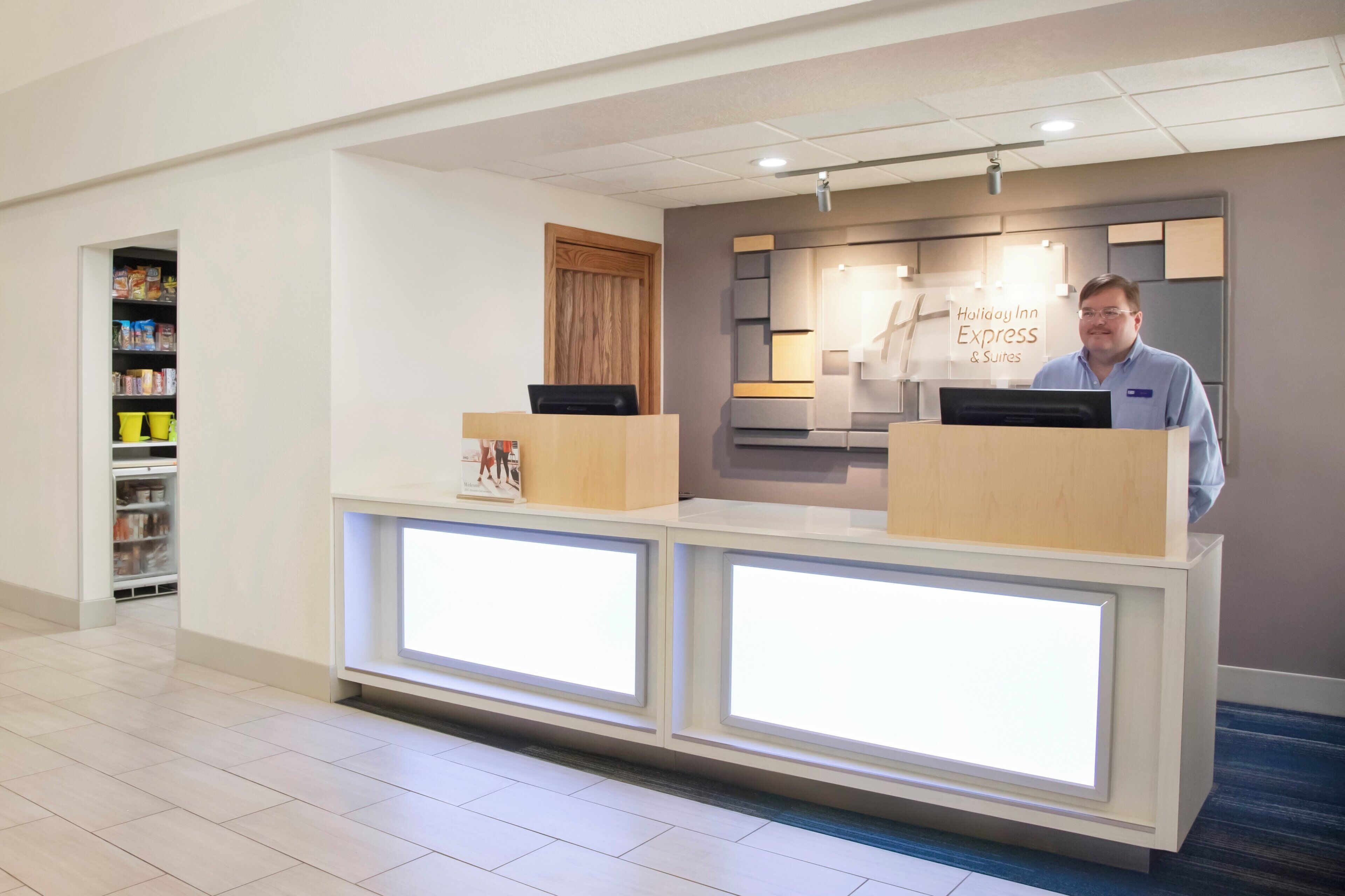 Uma receção com um ecrã digital, uma porta de madeira e um painel fixado na parede para Holiday Inn Express & Suites.