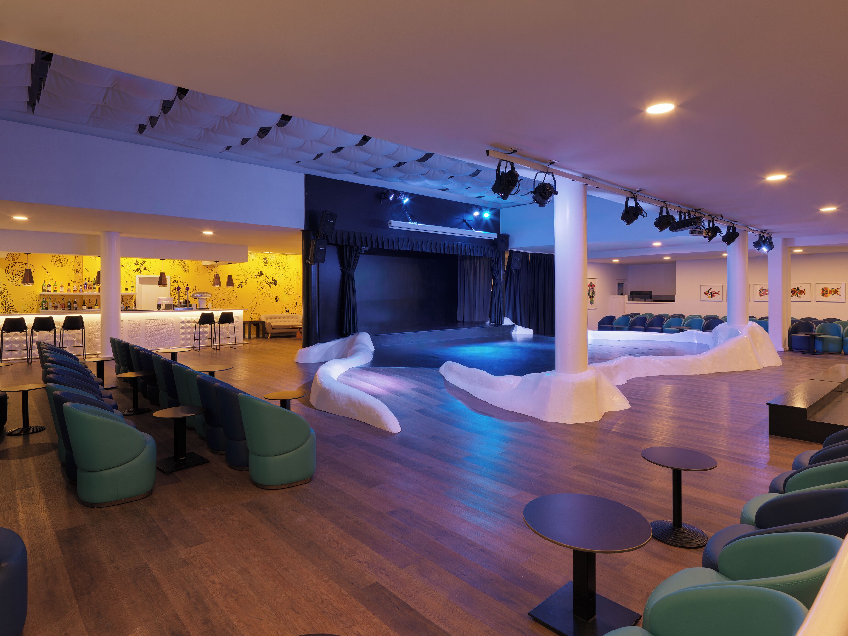 Uma área de estar moderna com assentos, bar e palco.