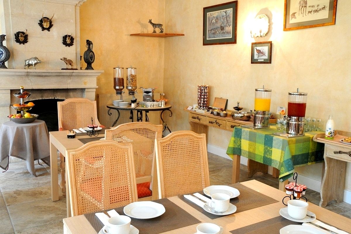 Uma área de café da manhã com lareira, cadeiras de vime, uma mesa posta com pratos, xícaras e um espaço para café.