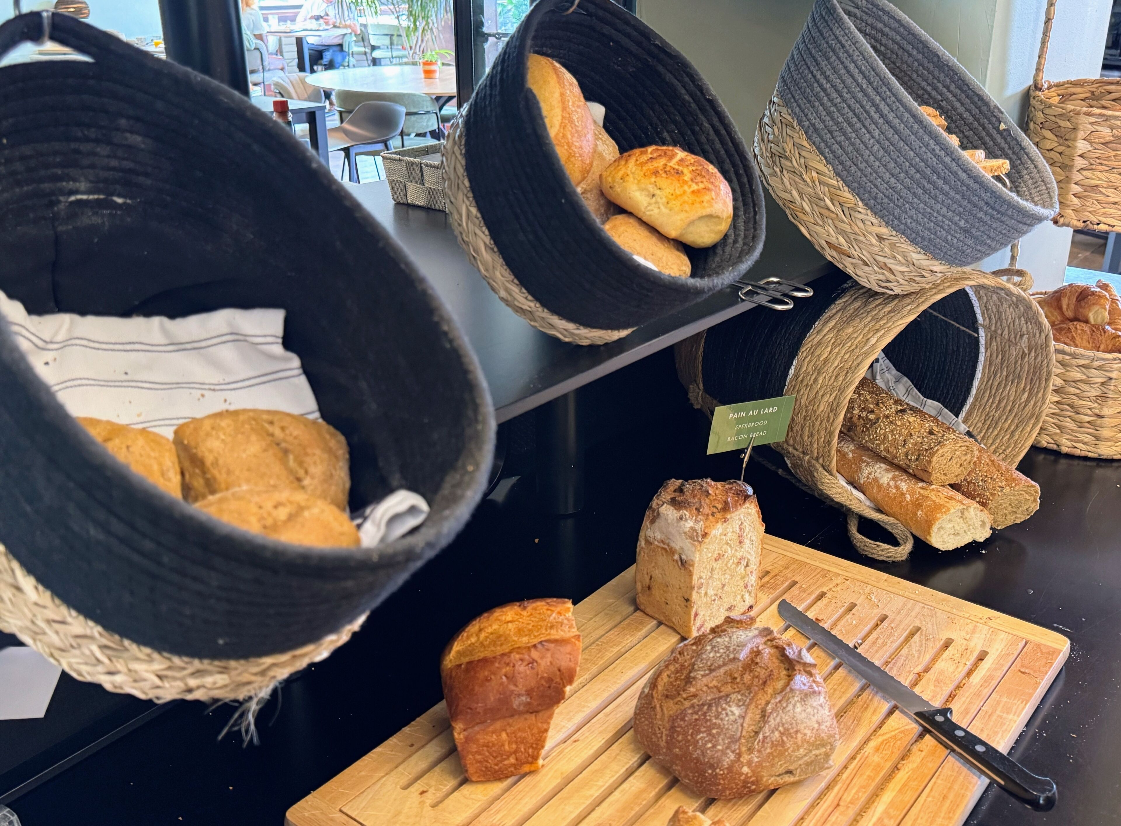 Cestos de pão sobre um balcão, com uma faca e uma tábua de corte.