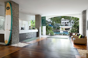 Uma área de recepção com um prancha de surf, balcão de recepção e vista para uma piscina e um edifício.