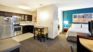 Quarto de hotel compacto com cozinha compacta, área de refeições, cama e televisão.