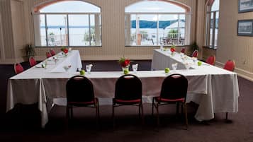Sala de conferências com uma mesa comprida, cadeiras vermelhas e amplas janelas com vista panorâmica.