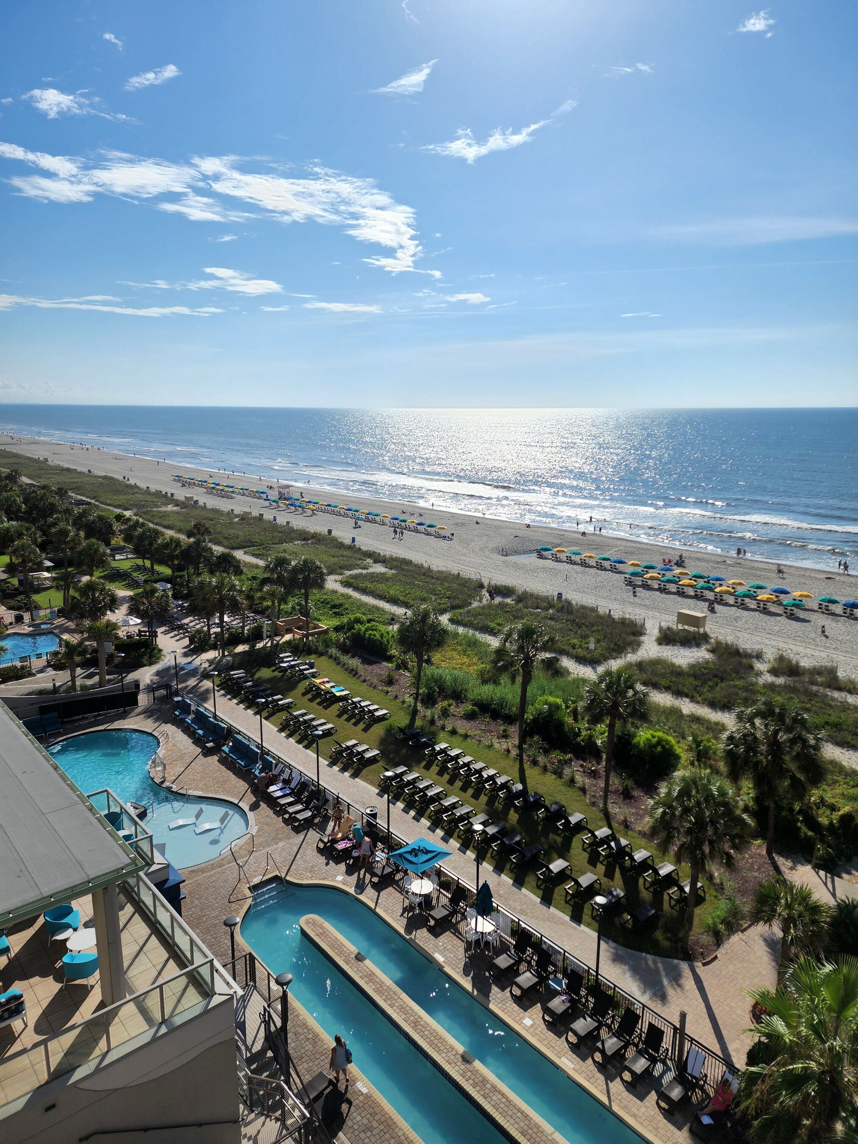 Um resort com área de piscina, espreguiçadeiras e vista para a praia e oceano.