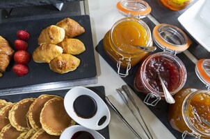 Um buffet de café da manhã com pães, morangos e diversas geleias.