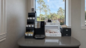 Cantinho de café com máquina Keurig, xícaras e balcão para café.