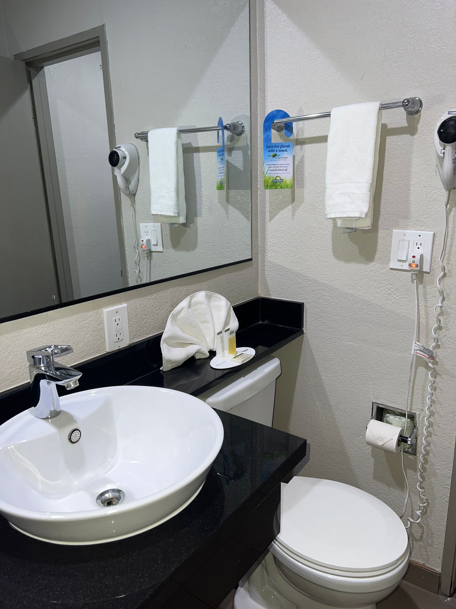 Um banheiro com pia branca, vaso sanitário, espelho e porta-toalhas.