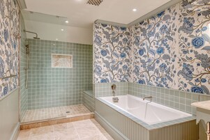 Casa de banho com chuveiro, banheira e azulejos com padrão floral.
