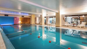 Piscina interior com água cristalina, divisórias de pista e boias vermelhas.