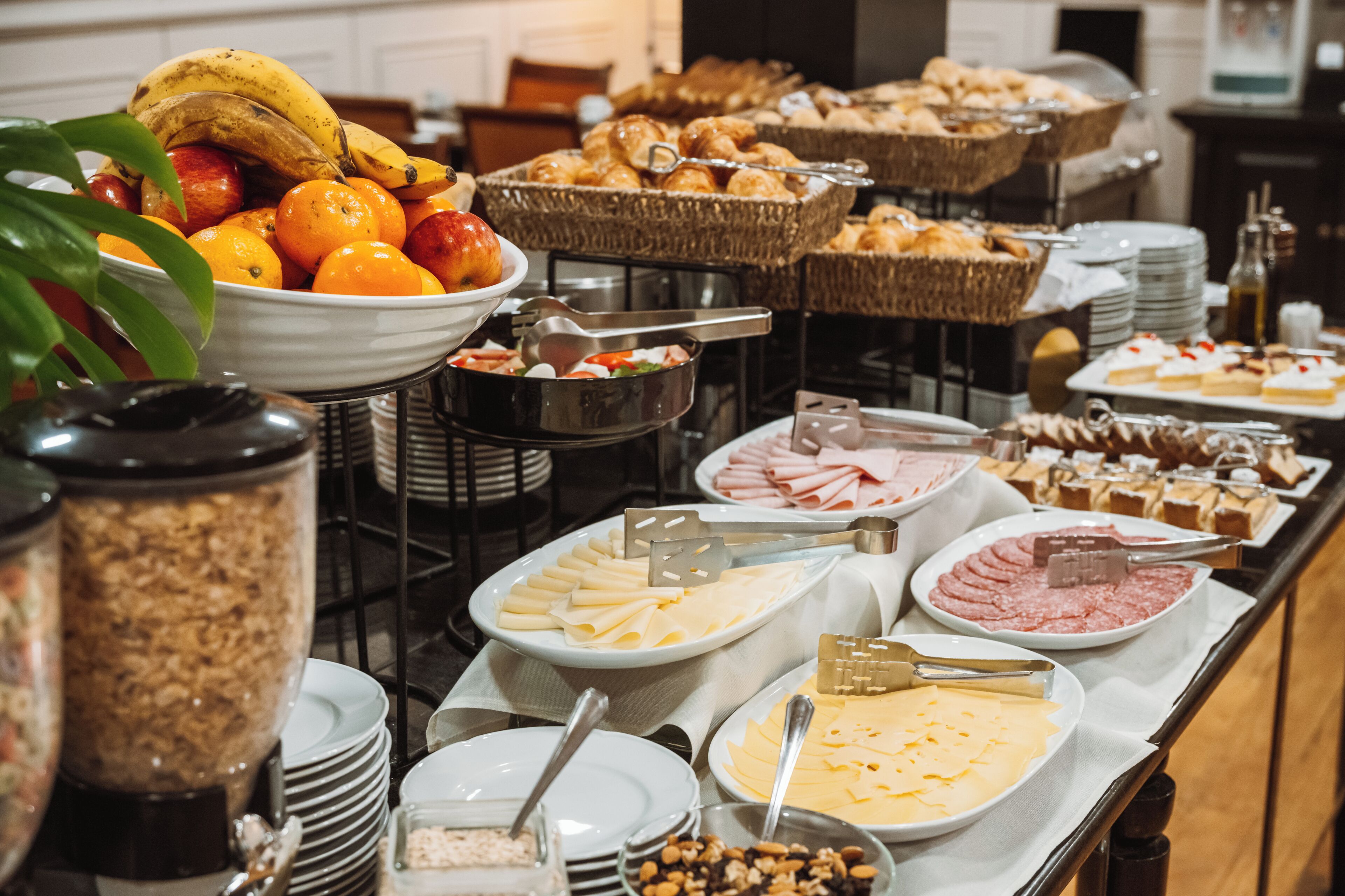 Buffet com diversos alimentos, incluindo frutas, queijos e doces.