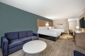 Quarto de hotel com cama, sofá, escrivaninha e cadeira.