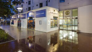 Um hotel com fachada moderna, várias entradas e exterior bem iluminado.