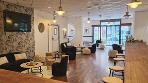 Uma área de estar moderna com sofás, mesas redondas e um balcão de bar.