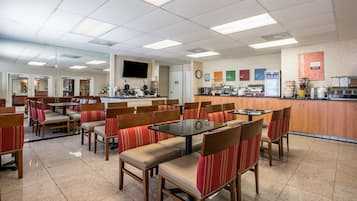 Uma cafeteria com cabines e mesas, um espaço para café e um relógio na parede.