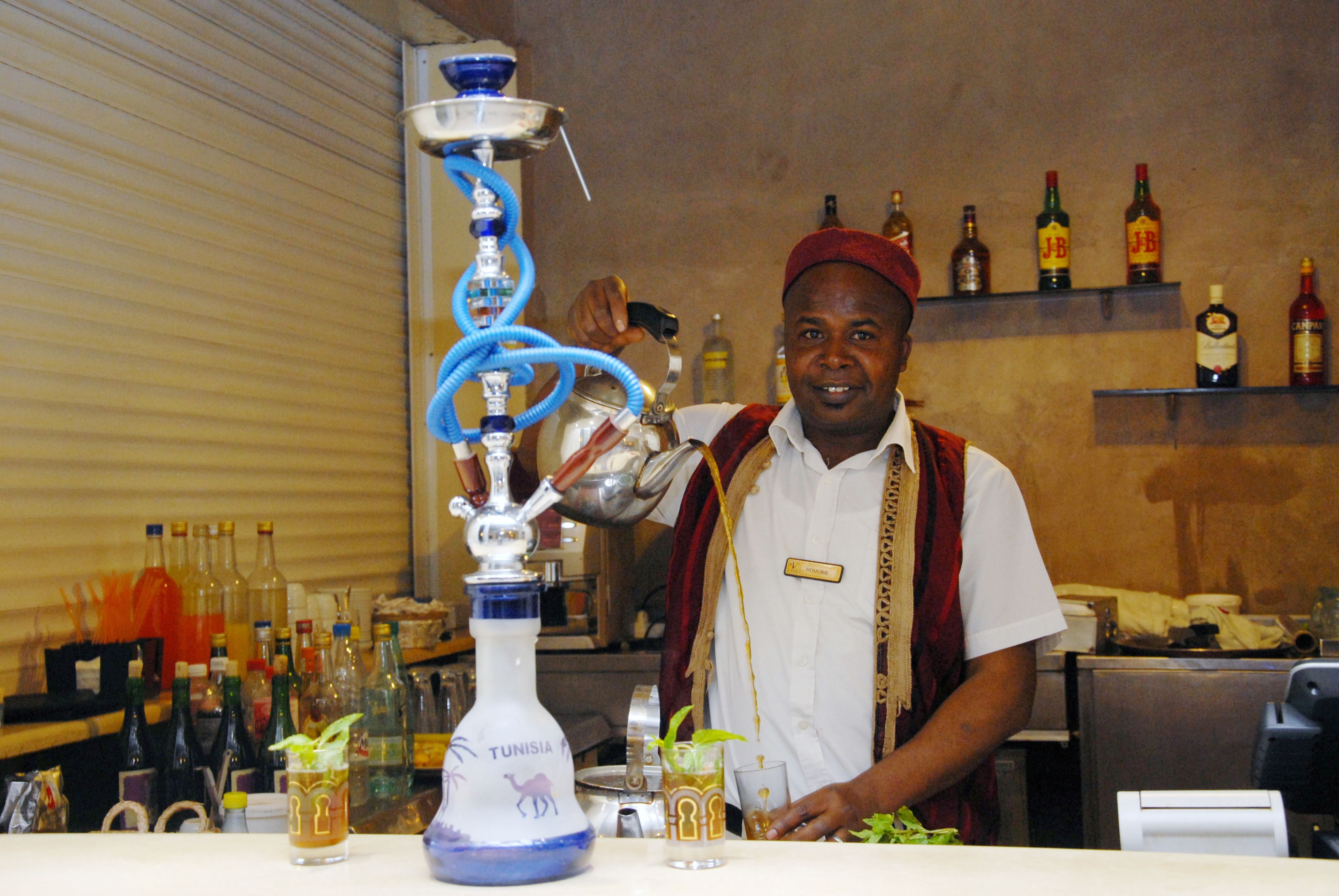 Um bar com narguilé e diversas garrafas de bebidas alcoólicas.