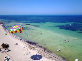 Na praia, espreguiçadeiras, guarda-sóis, prática de esqui aquático 