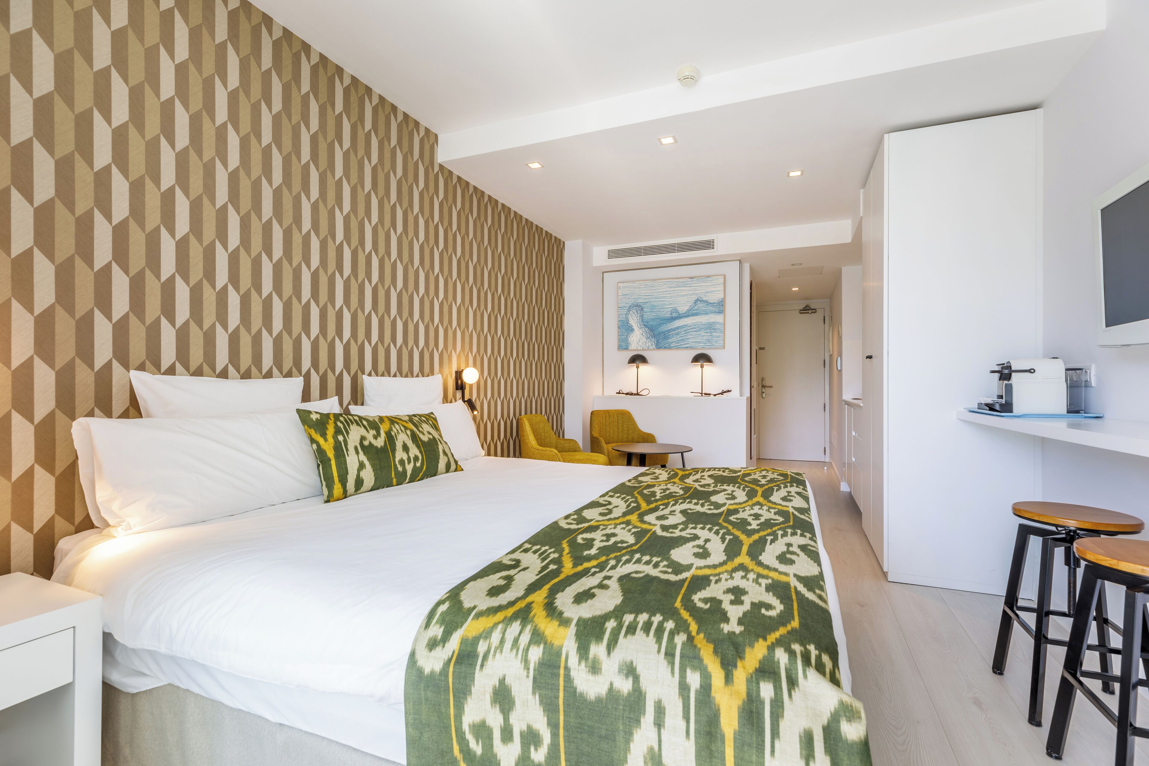 Quarto de hotel moderno com uma cama grande, uma escrivaninha e uma cadeira.