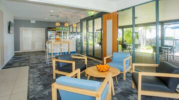 Uma área de estar moderna com poltronas estofadas em azul e uma mesa de centro de madeira, com uma fruteira.