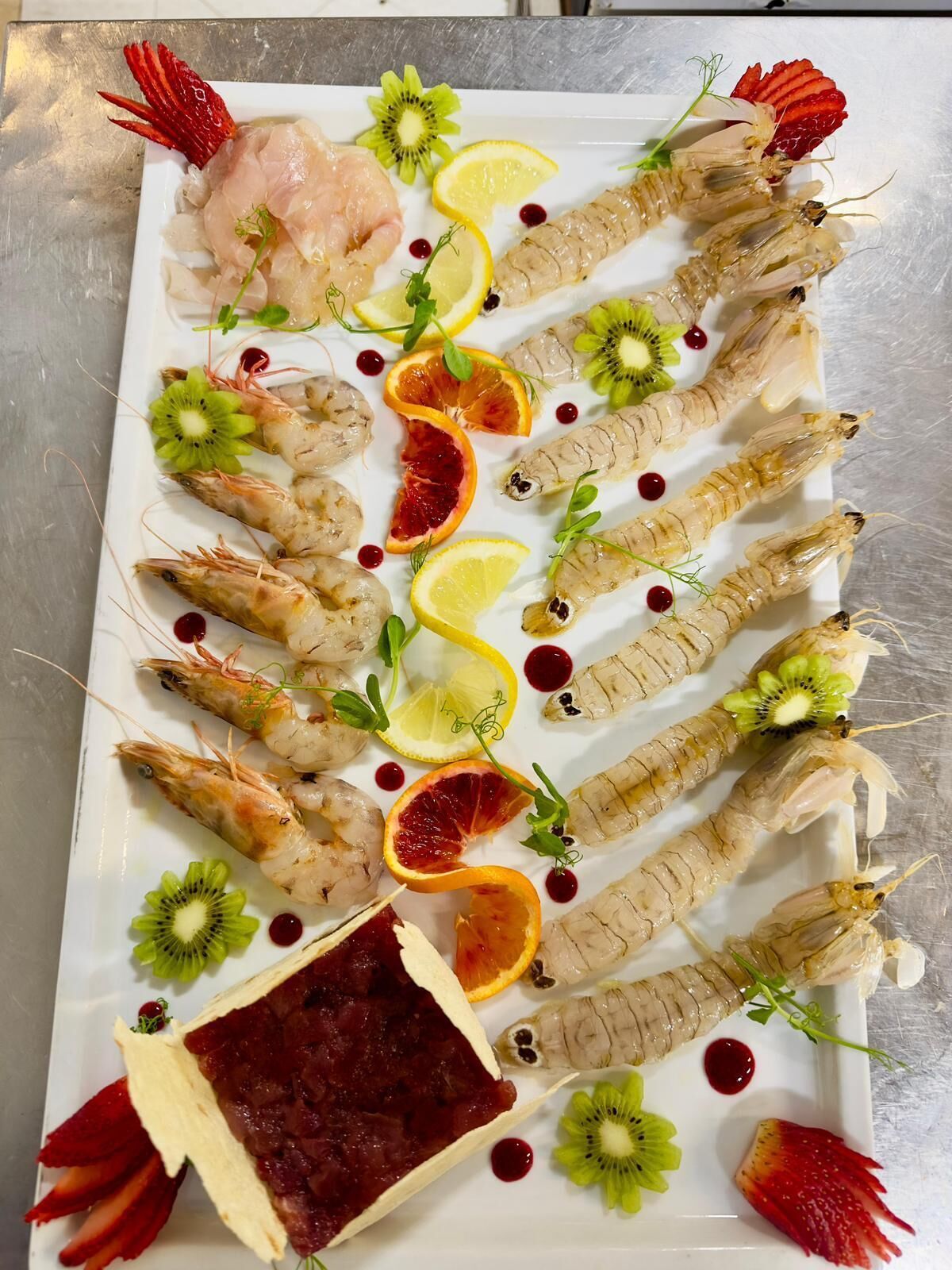 Prato de frutos do mar com camarões, fatias de limão, kiwi e morangos.