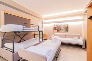 Quarto de hotel com beliches, sofá e um quadro na parede.