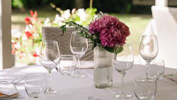 Uma mesa posta para refeição, com copos transparentes e um vaso de flores.