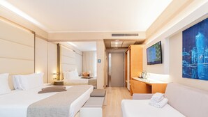 Quarto de hotel com duas camas, um sofá, uma escrivaninha e um quadro na parede.