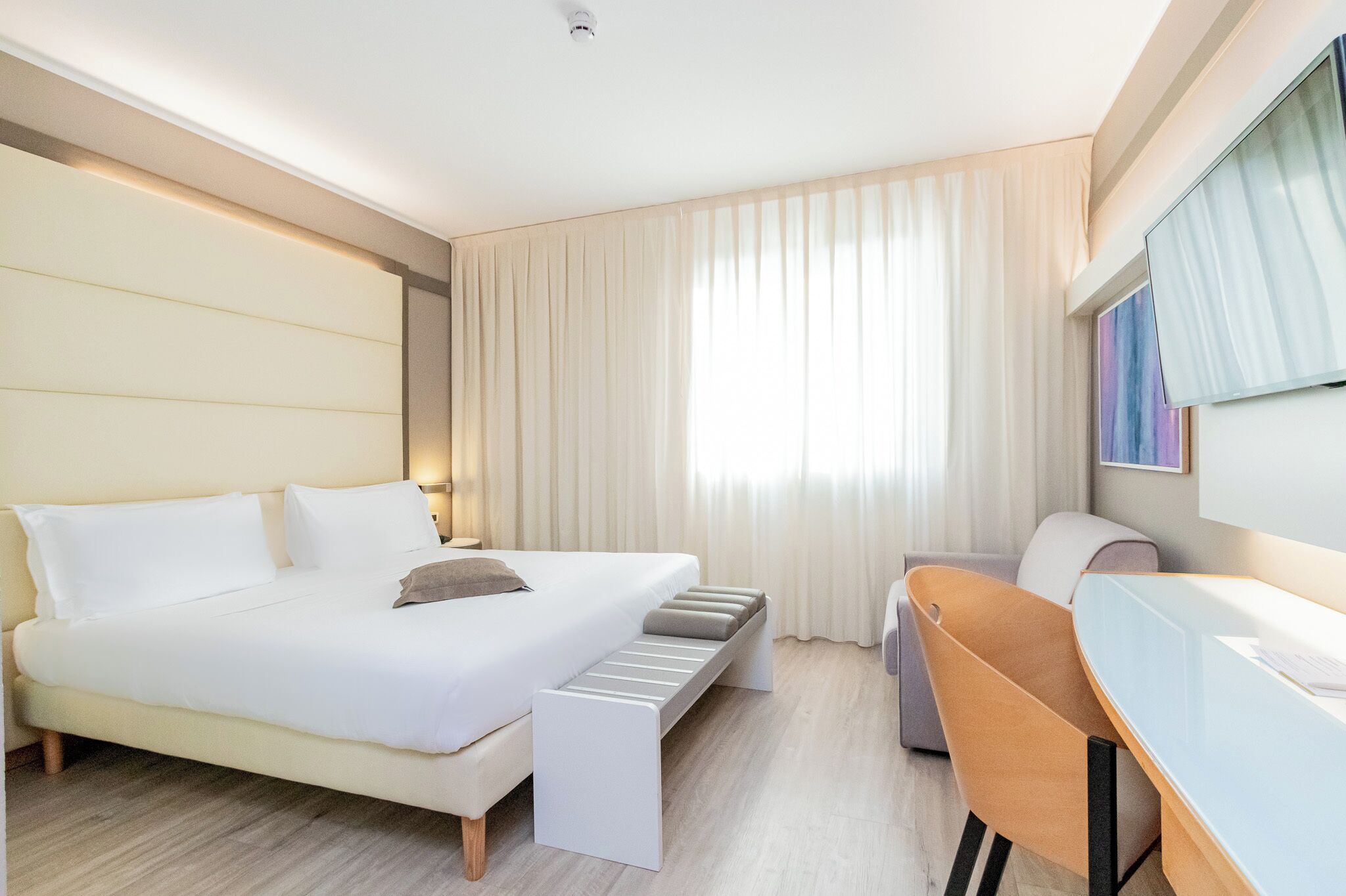 Quarto de hotel moderno com uma cama grande, uma escrivaninha e uma cadeira.