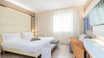Quarto de hotel moderno com uma cama grande, uma escrivaninha e uma cadeira.