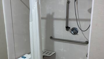 Box de chuveiro com cortina branca, chuveiro manual, torneira fixada na parede e barra de apoio.
