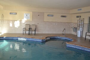 Piscina interior com borda revestida, elevador de piscina e uma cadeira.